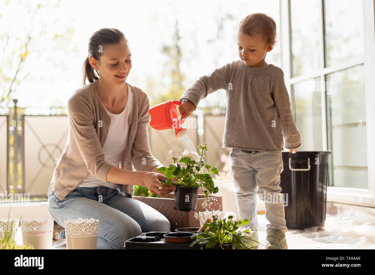 Mother and daughter planting flowers together on balcony Stock Photo ...