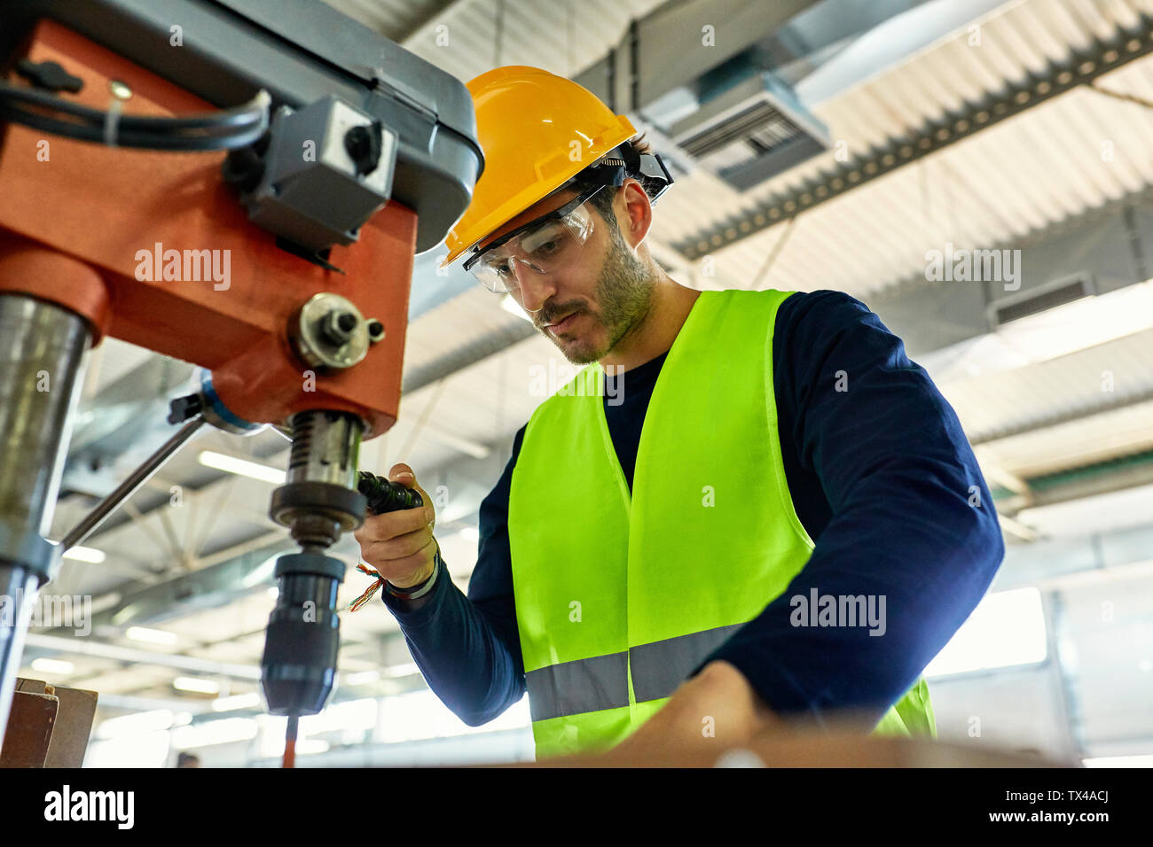 Worker operating drill in factory Stock Photo - Alamy