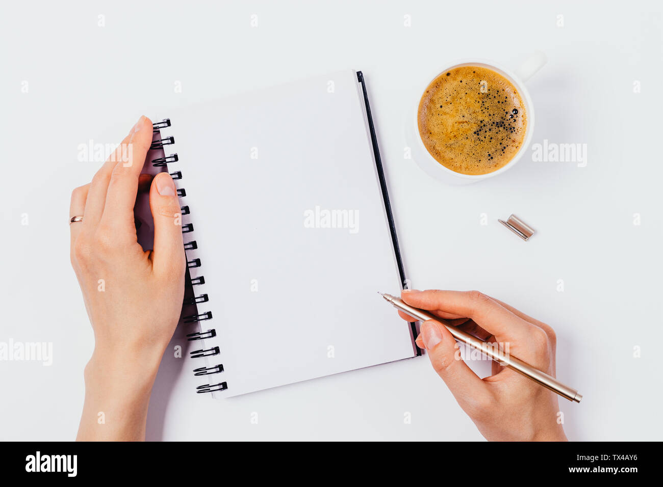 Flat lay composition of female's hands writing in an empty notebook ...