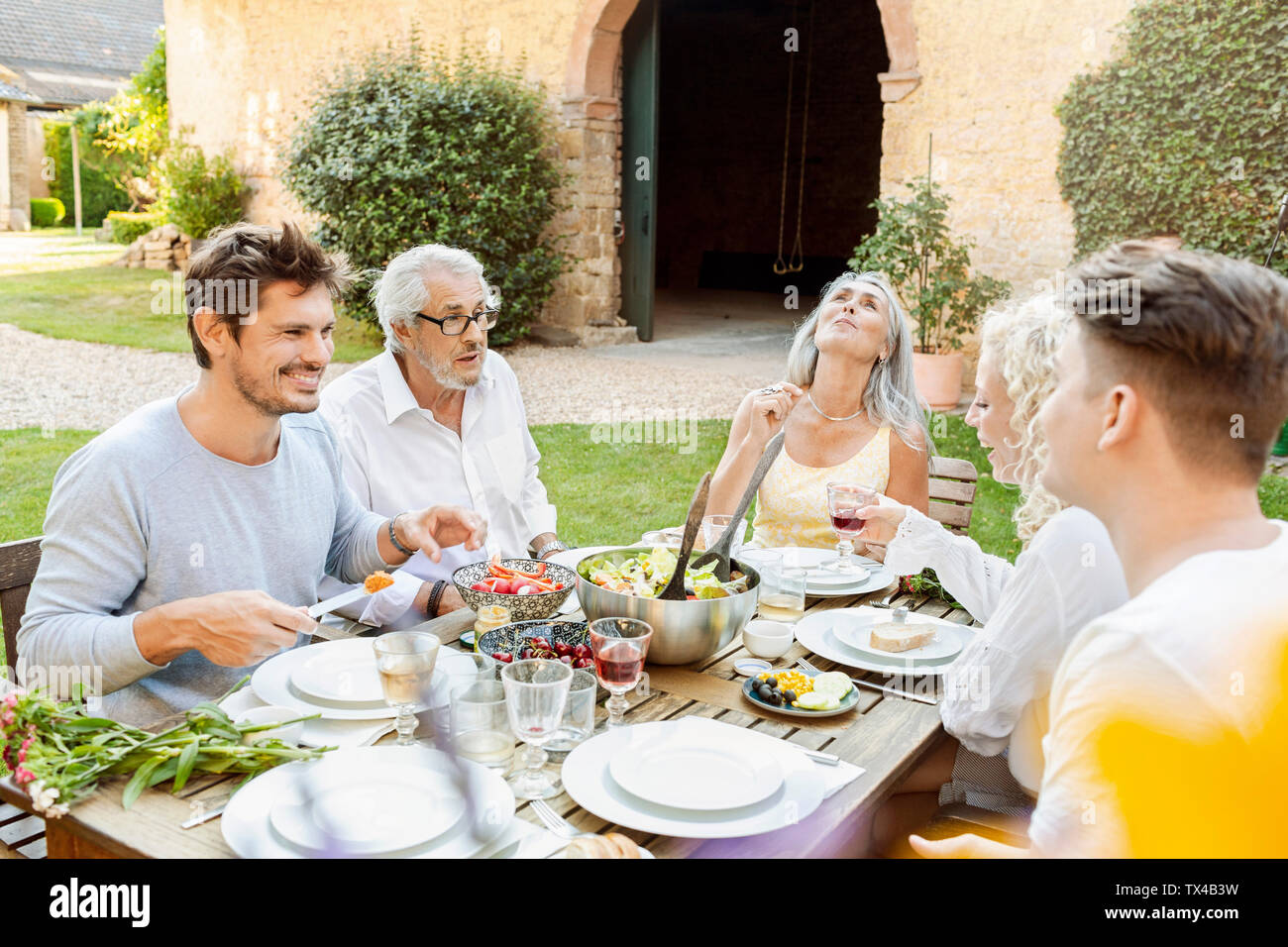 Happy family eating together in the garden Stock Photo - Alamy