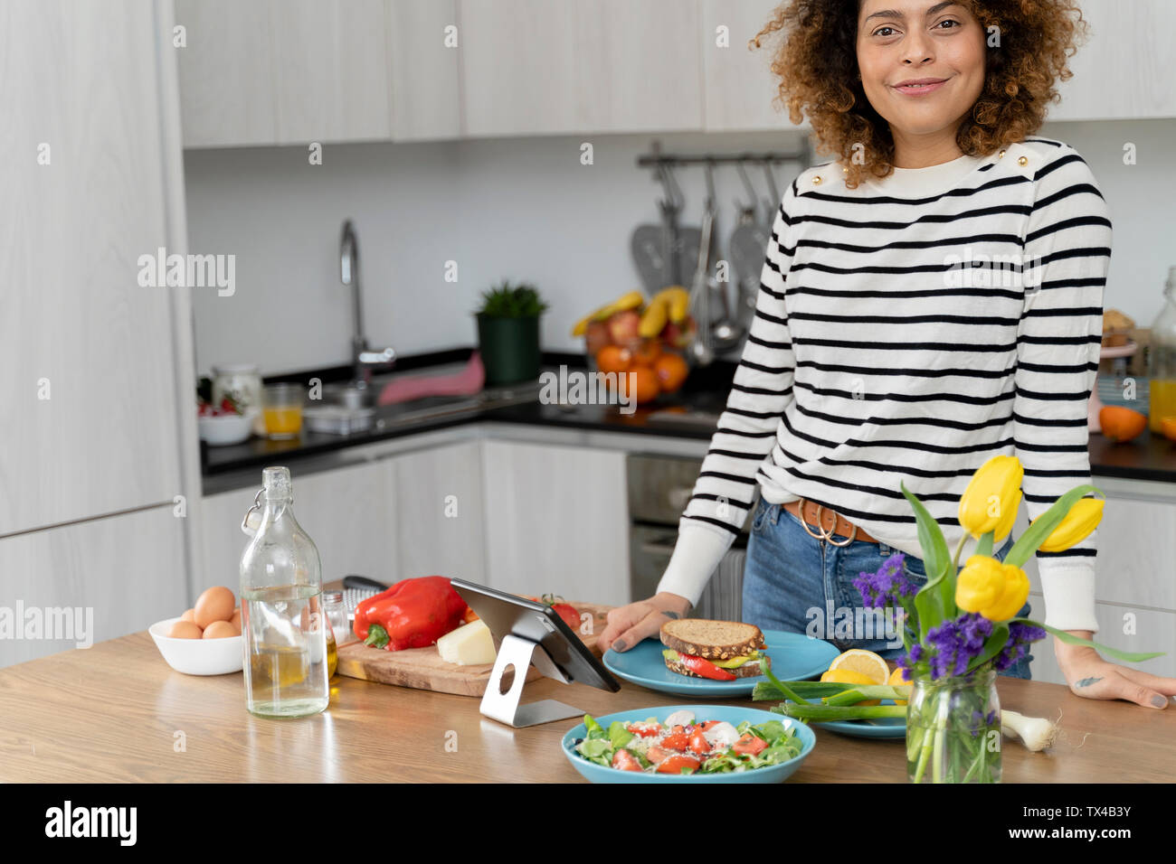 Woman standing in kitchen, preparing salad for lunch Stock Photo - Alamy