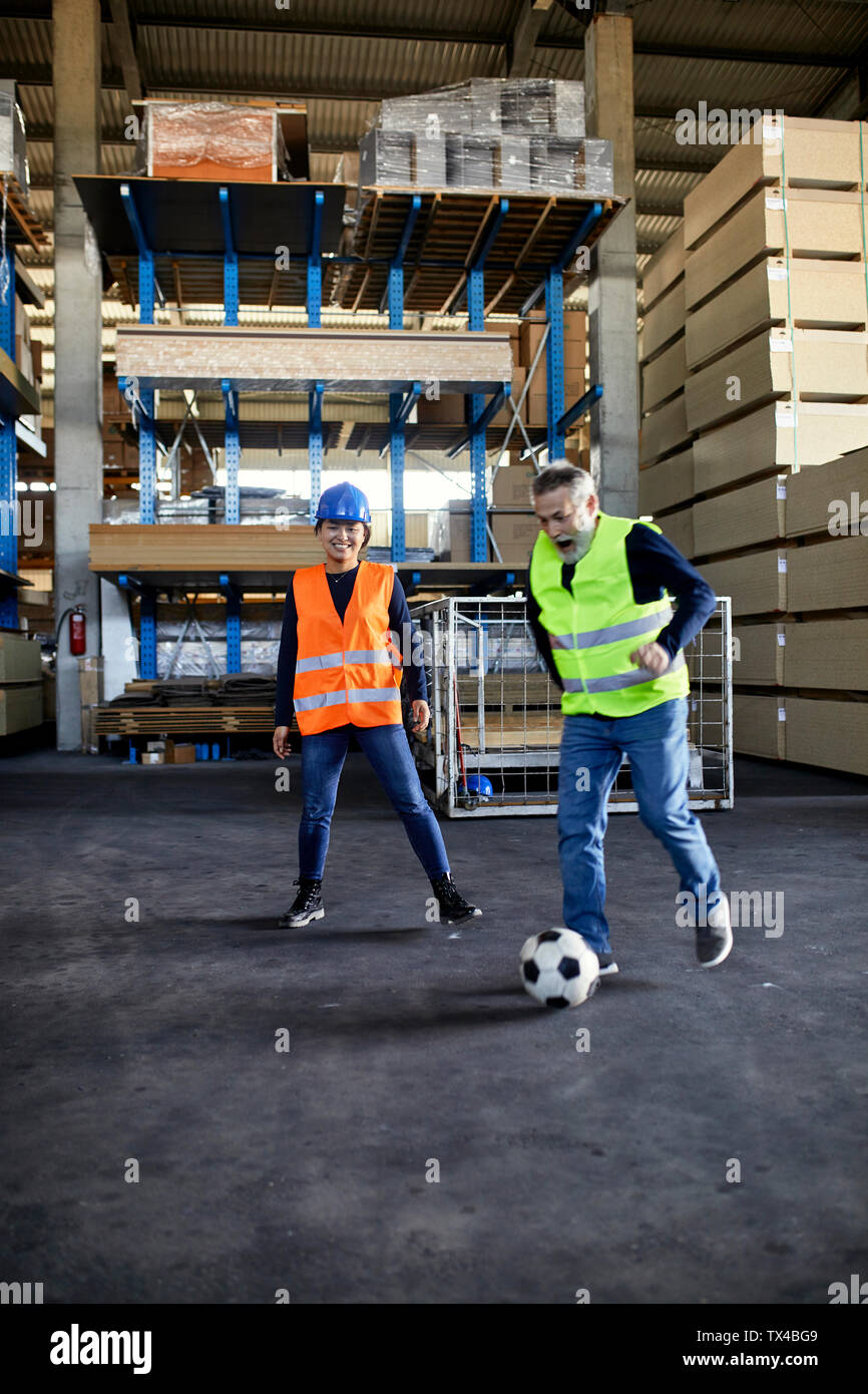 Workers playing football in factory warehouse Stock Photo - Alamy