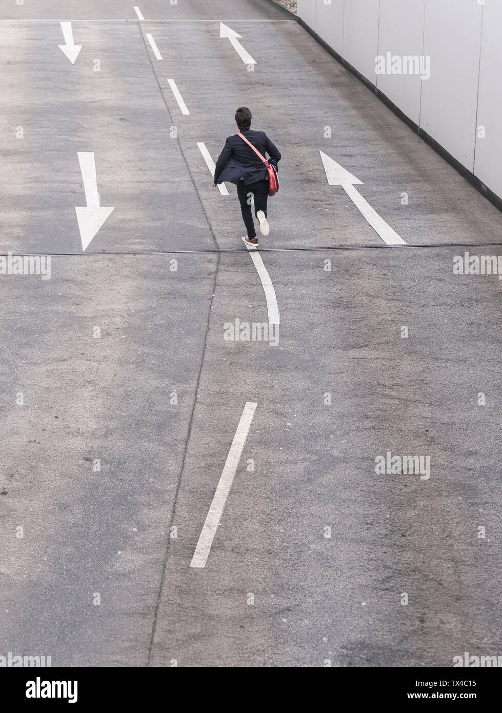 Rear view of businessman running on road with arrow signs Stock Photo ...