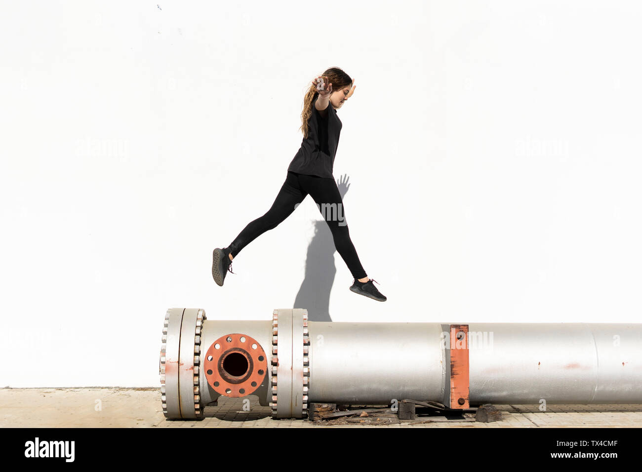 Teenage girl jumping over large pipe outdoors Stock Photo - Alamy
