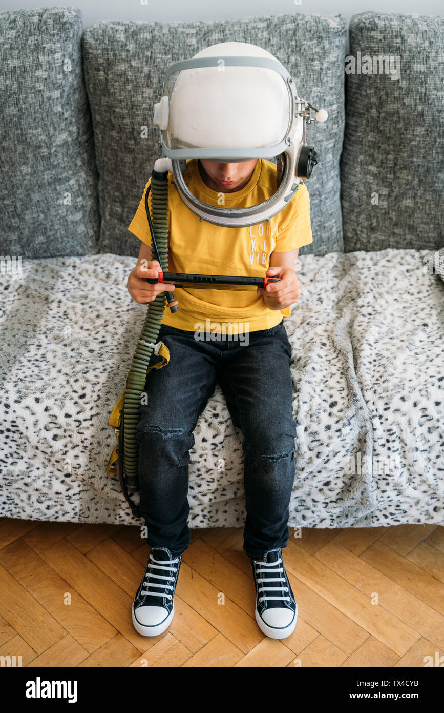 Boy playing video game on a games console, wearing space hat Stock ...