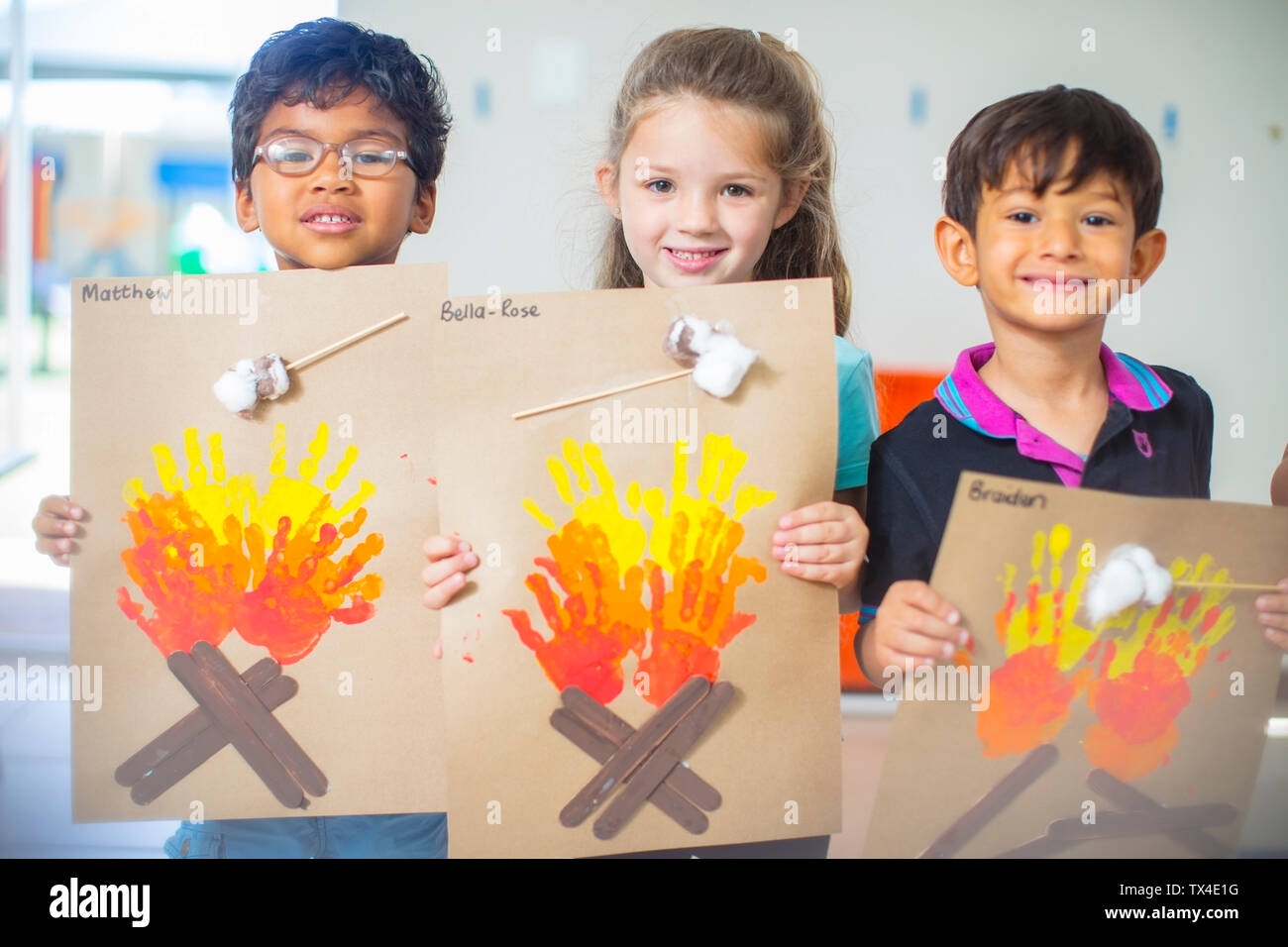 Portrait of smiling children presenting images of fire in kindergarten ...