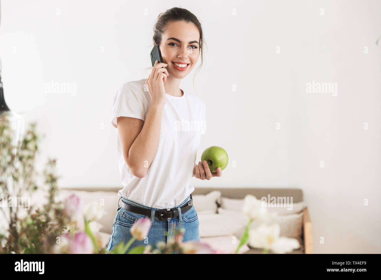 Image of a happy beautiful young student girl eat apple posing indoors ...
