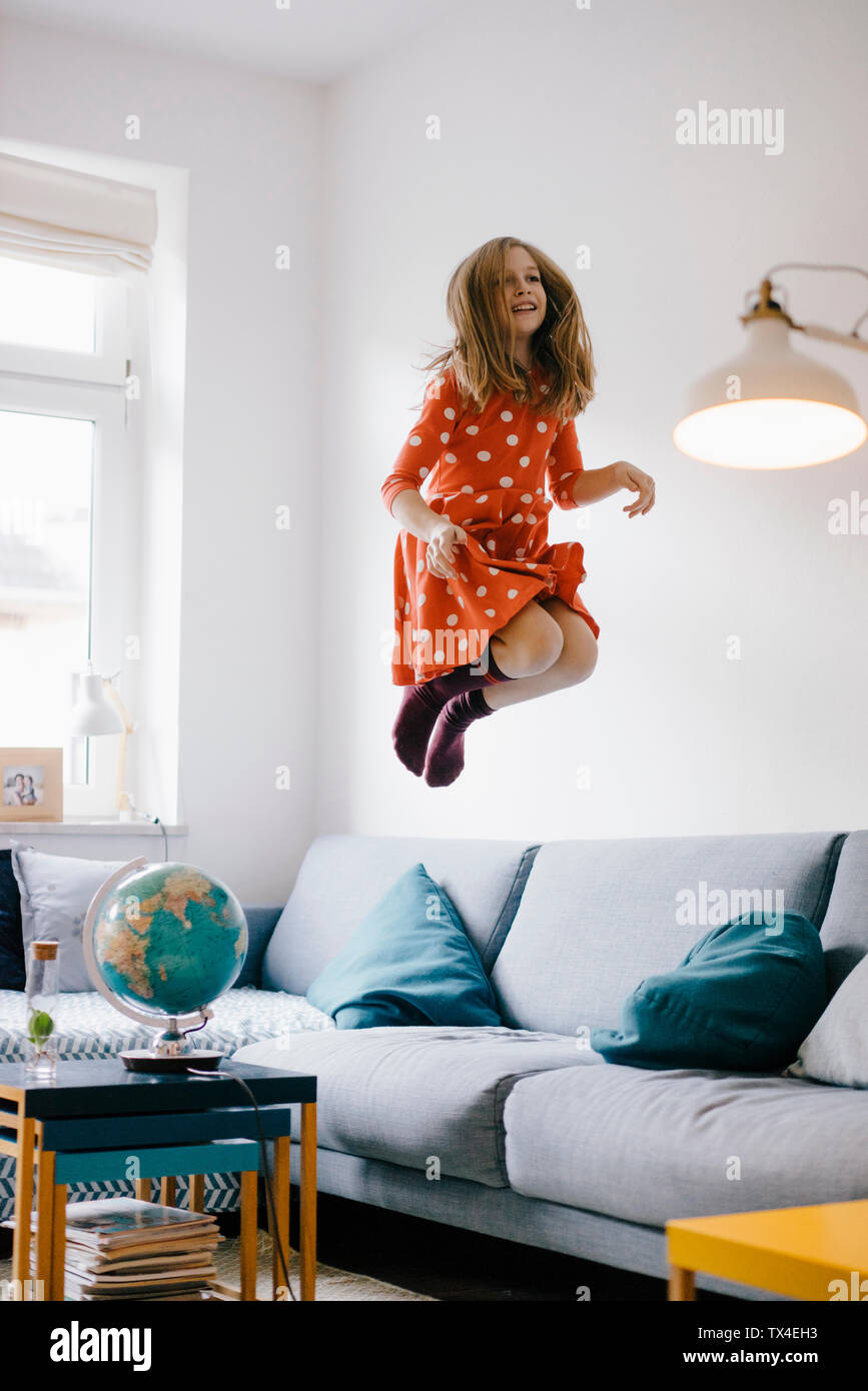 Carefree girl jumping on couch at home Stock Photo - Alamy