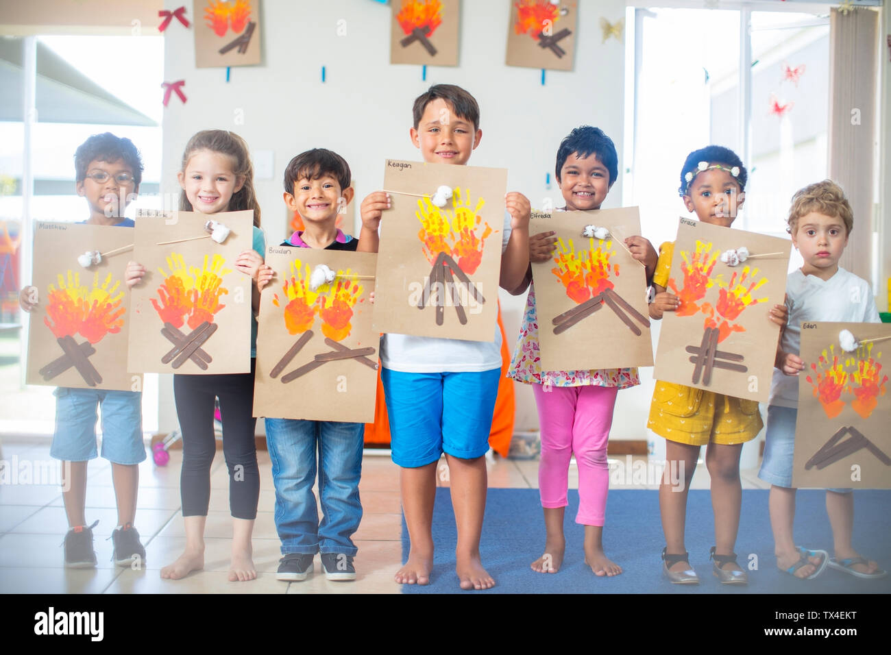 Portrait of smiling children presenting images of fire in kindergarten ...
