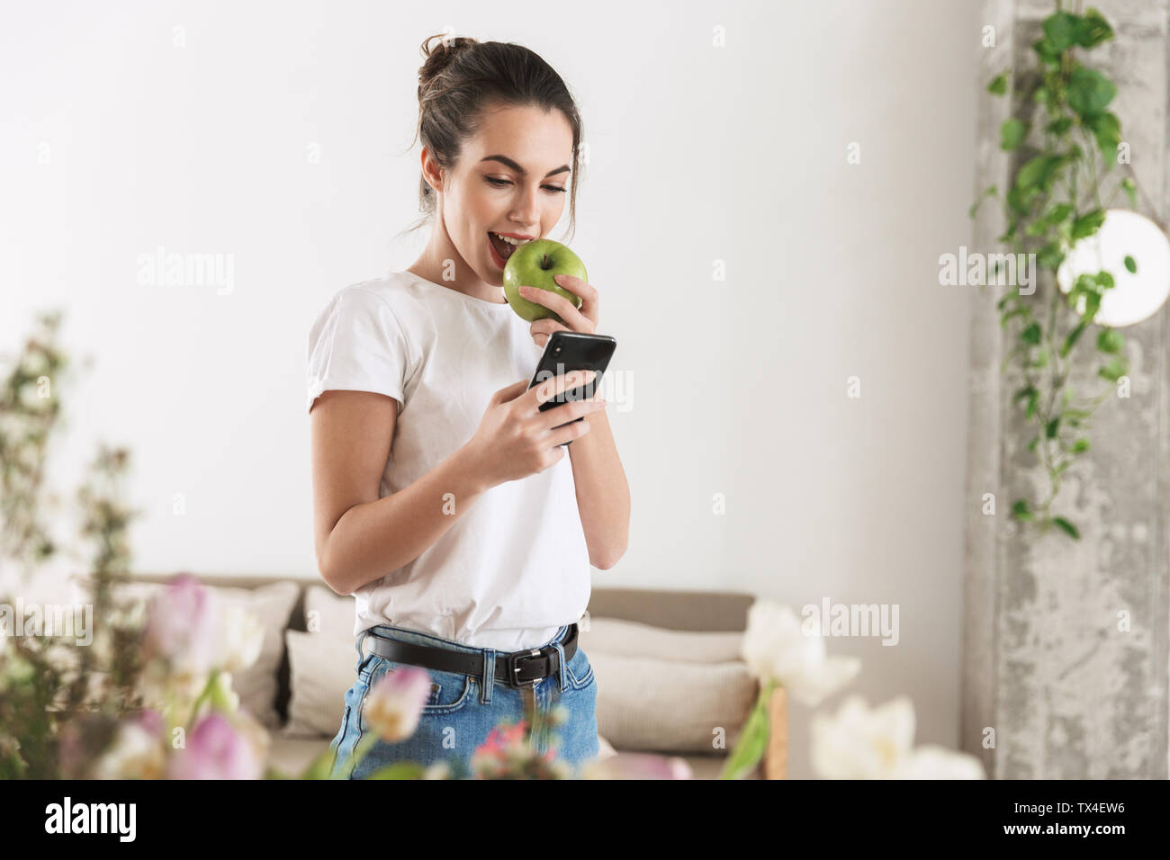 Image of a happy beautiful young student girl eat apple posing indoors ...