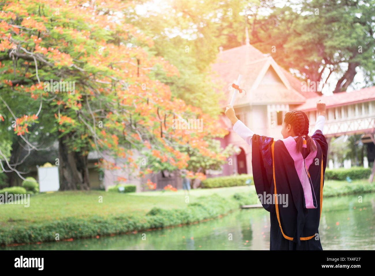 Happy and glad graduated Asian student girl standing and showing hand ...