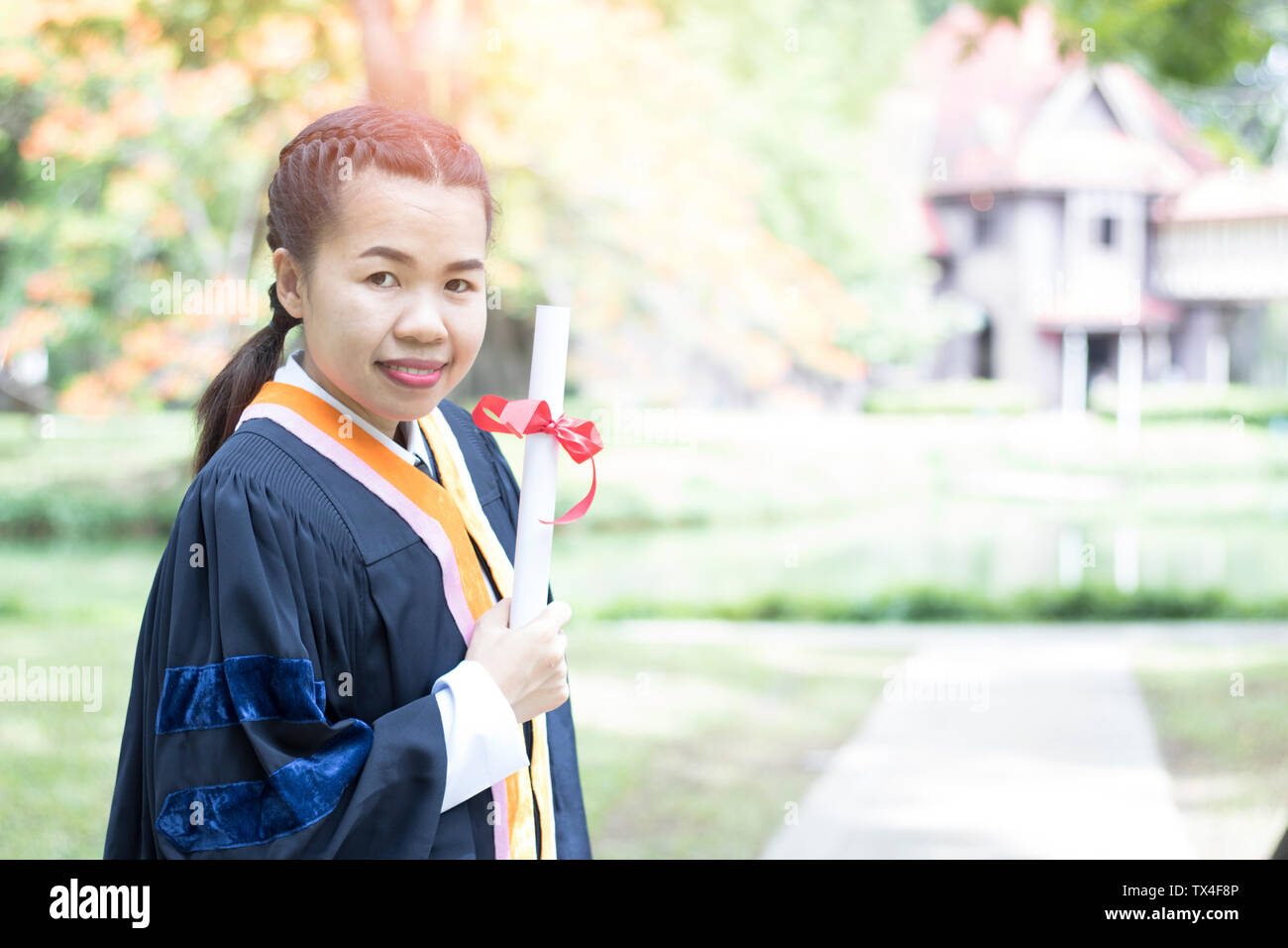 Happy and glad graduated Asian student girl standing and holding ...