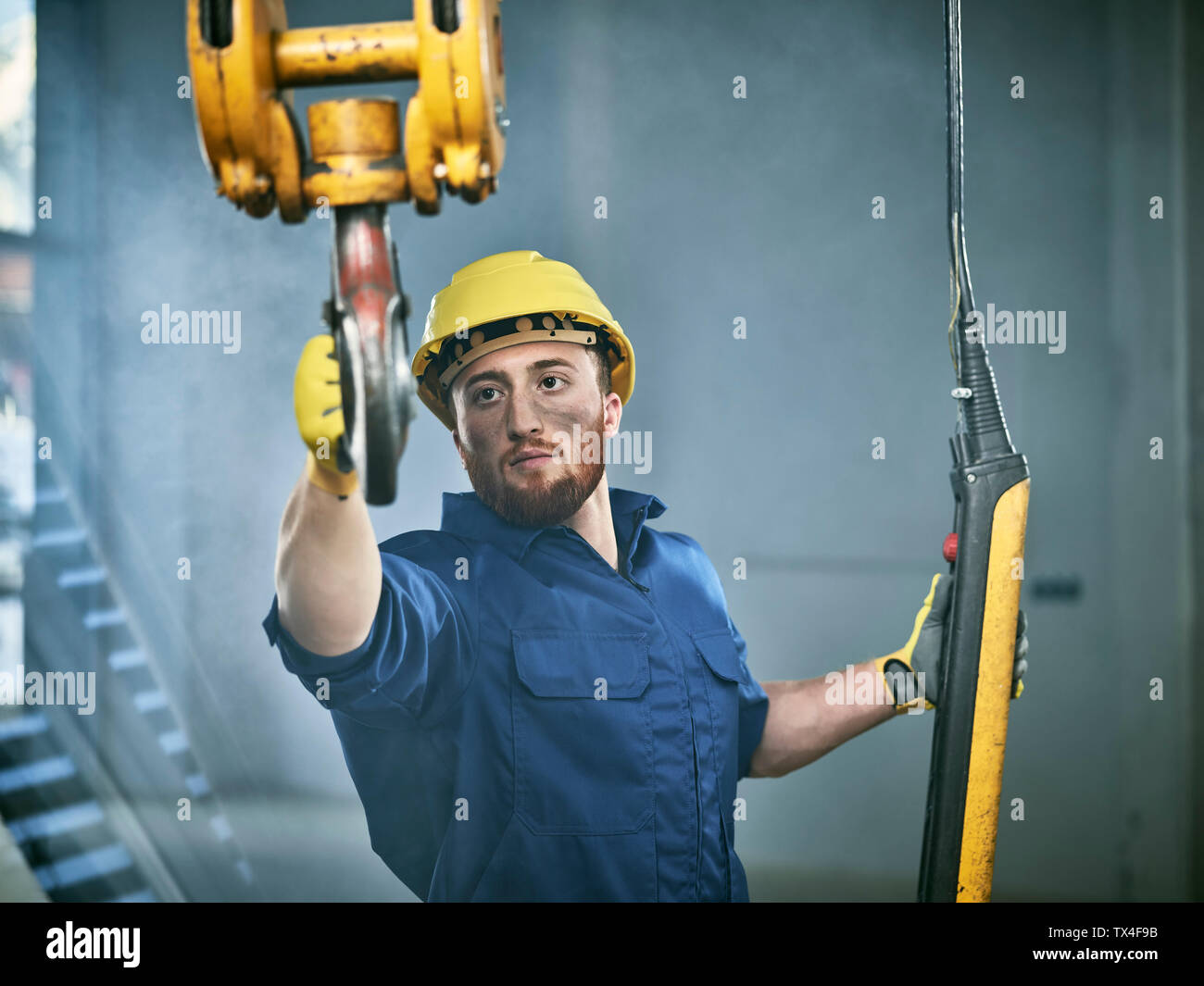 Industrial worker using hand control of indoor crane Stock Photo - Alamy