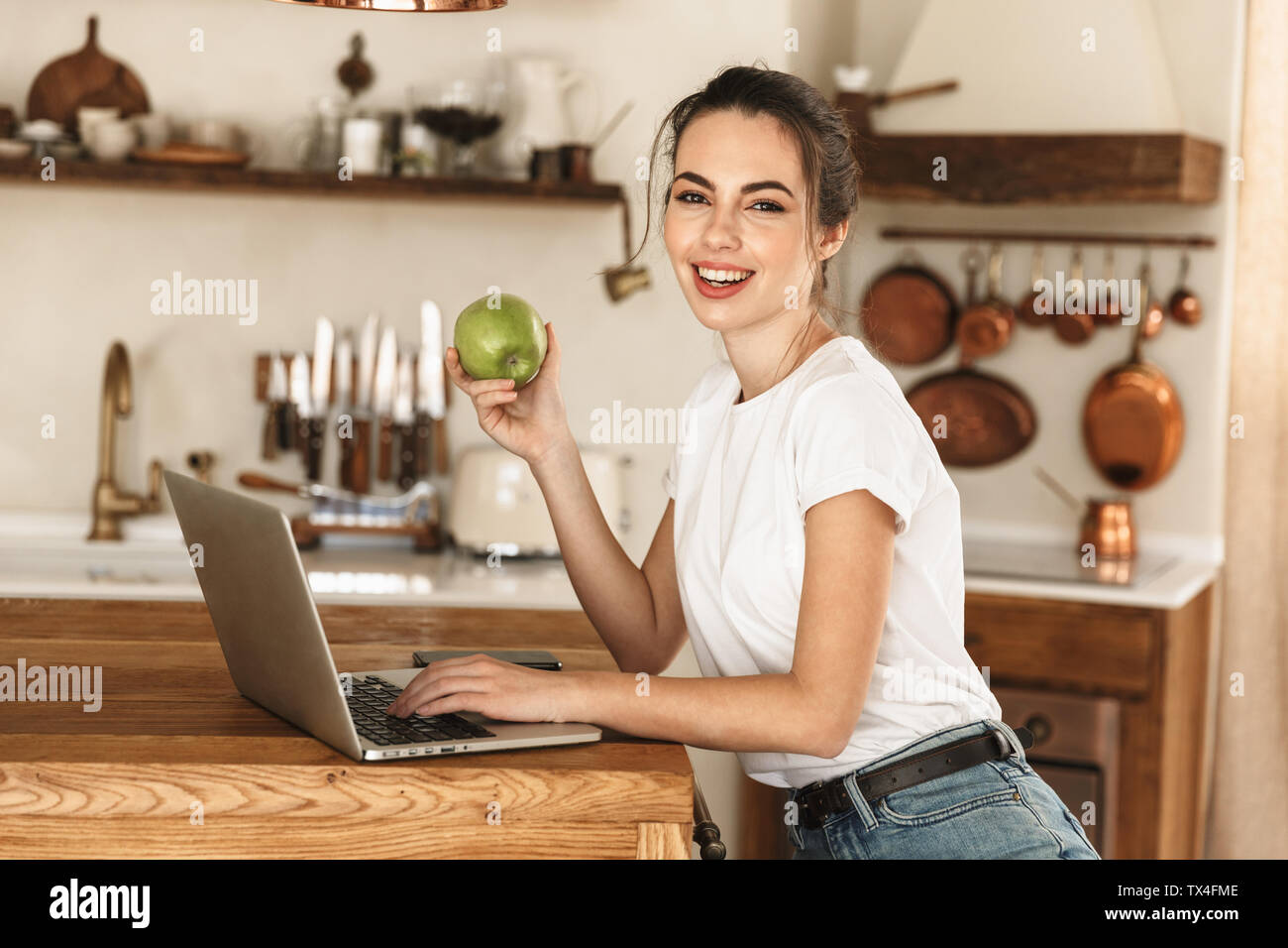 Image of a beautiful young student girl sitting indoors using laptop ...