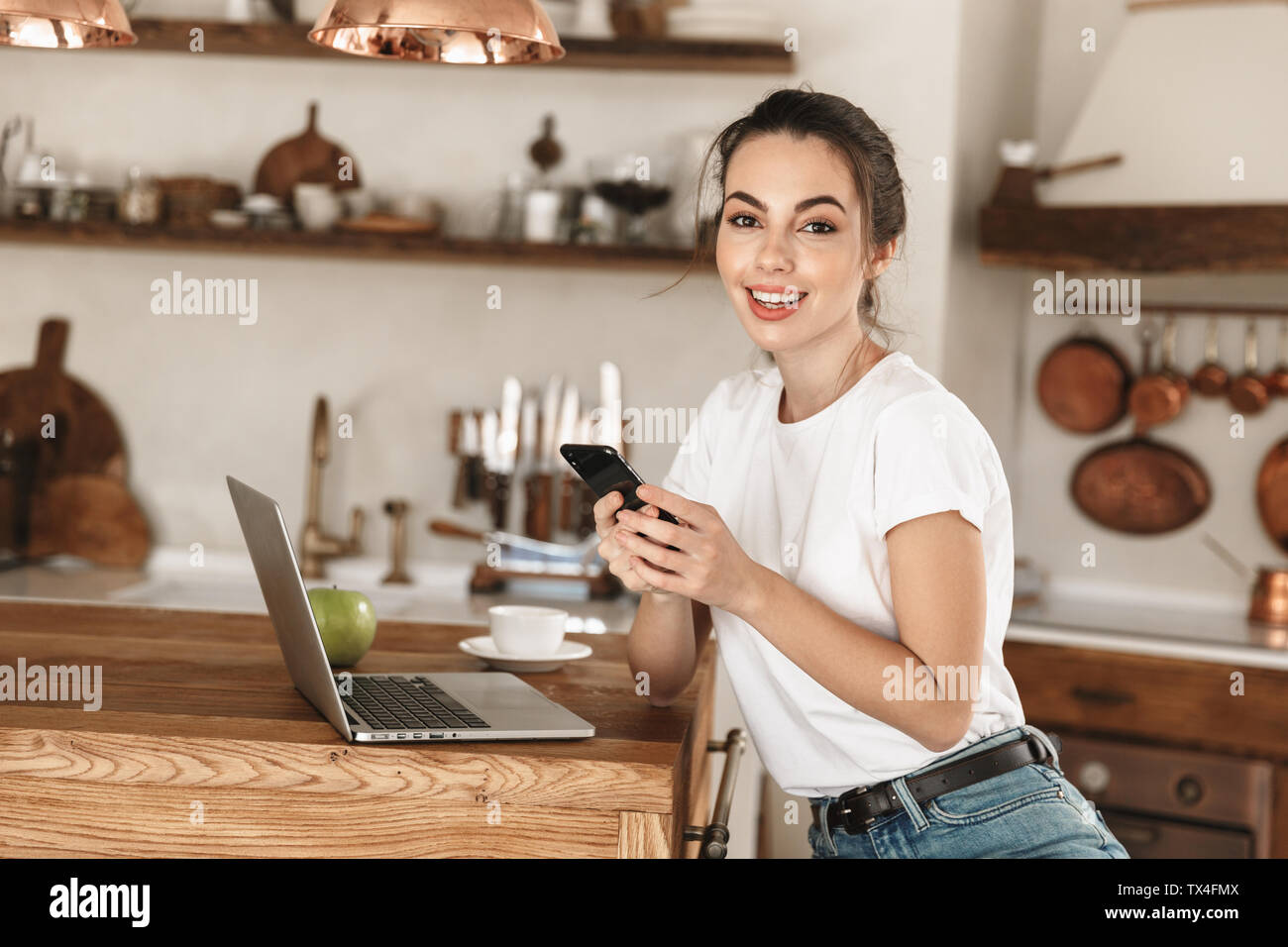 Image of a beautiful young student girl sitting indoors using laptop ...
