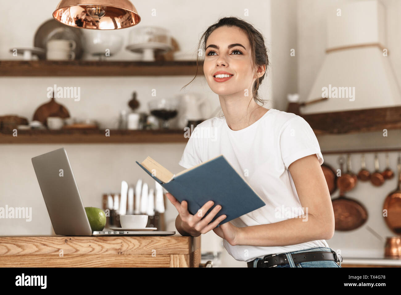 Image of a beautiful happy young student girl sitting indoors using ...