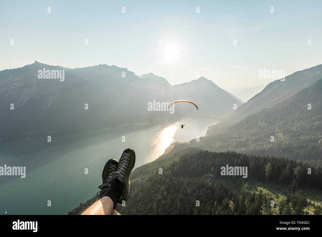 Austria, Tyrol, Legs of a man, watching paraglider over lake Achensee ...