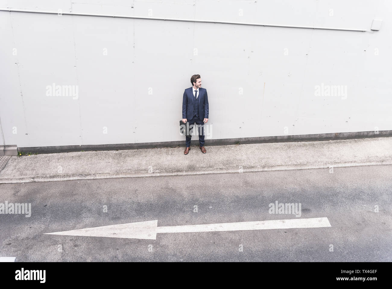 Businessman standing at road with arrow sign Stock Photo - Alamy