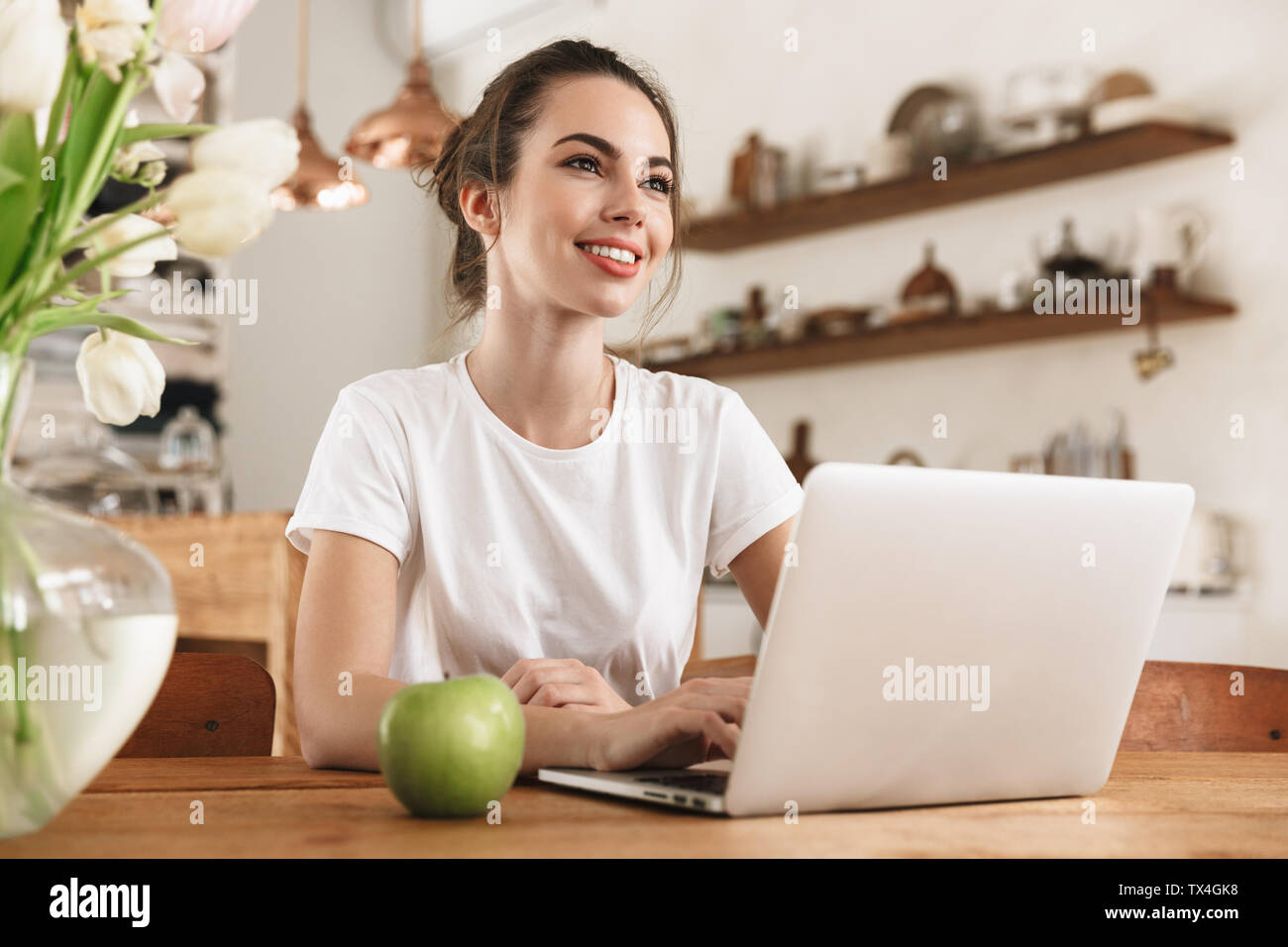 Image of a beautiful young student girl sitting indoors using laptop ...