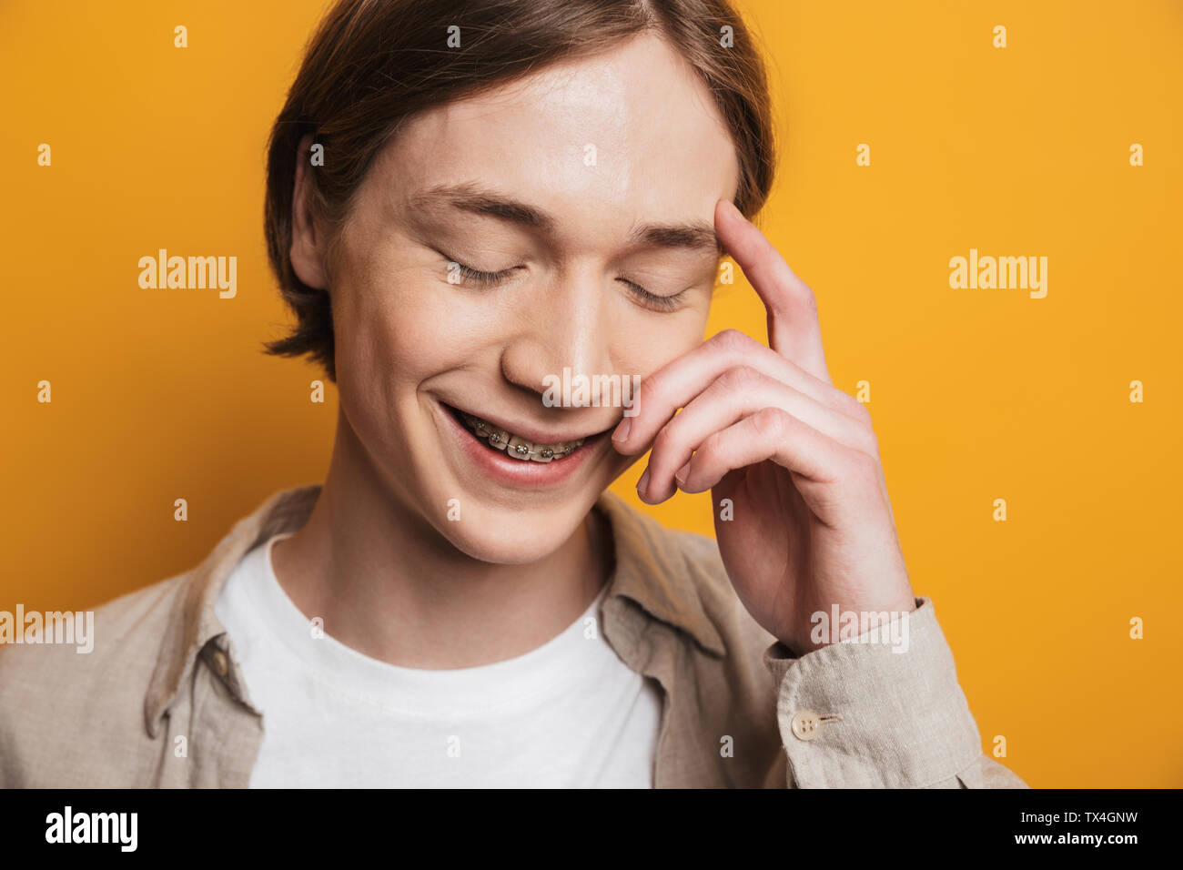 Close up image of Smiling shy handsome man in shirt posing with closed ...