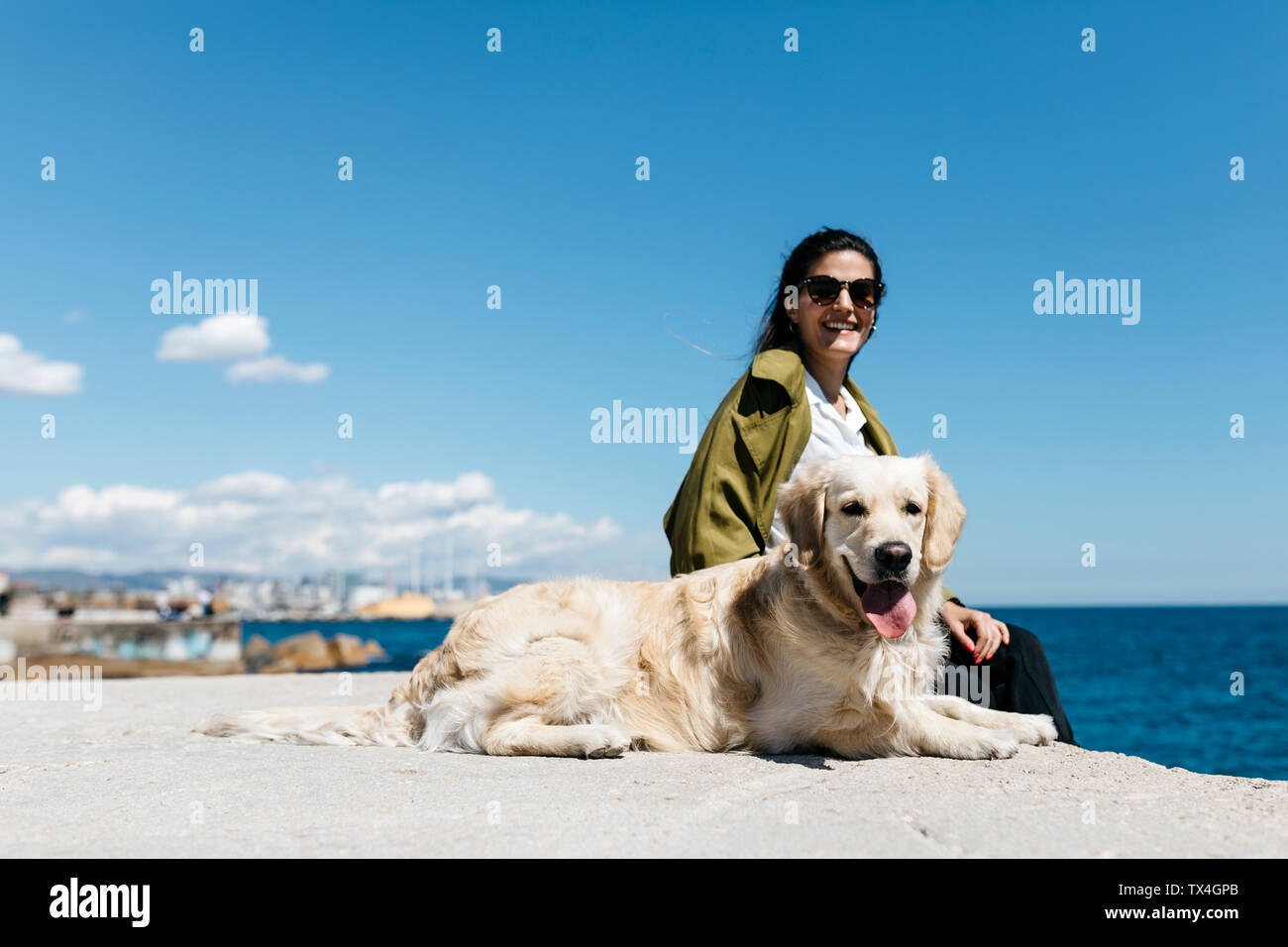 Happy woman sitting besides her Labrador Retriever at quay Stock Photo ...