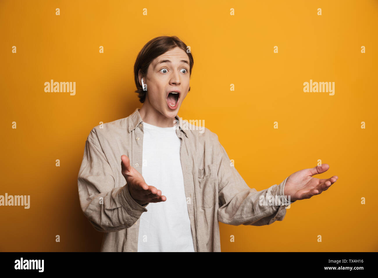 Shocked screaming handsome man in shirt looking away with open mouth ...