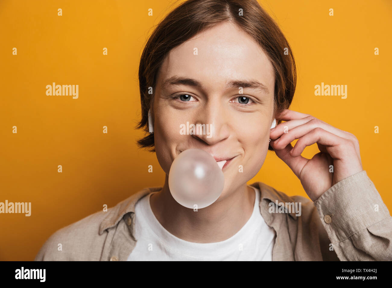 Happy handsome man in shirt listening music and looking at the camera ...