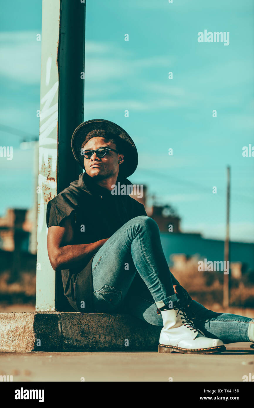 Young man sitting on the floor with a hat, looking sideways Stock Photo ...