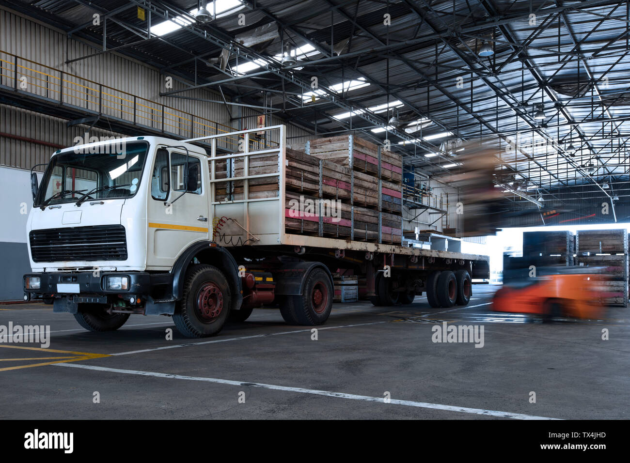 Forklift loading crates on parked truck in warehouse Stock Photo - Alamy