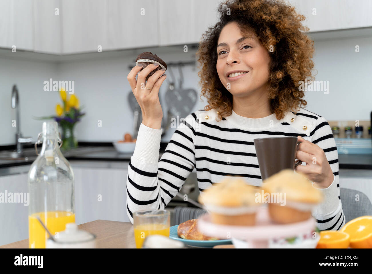 Woman sitting in kitchen, having breakfast Stock Photo - Alamy
