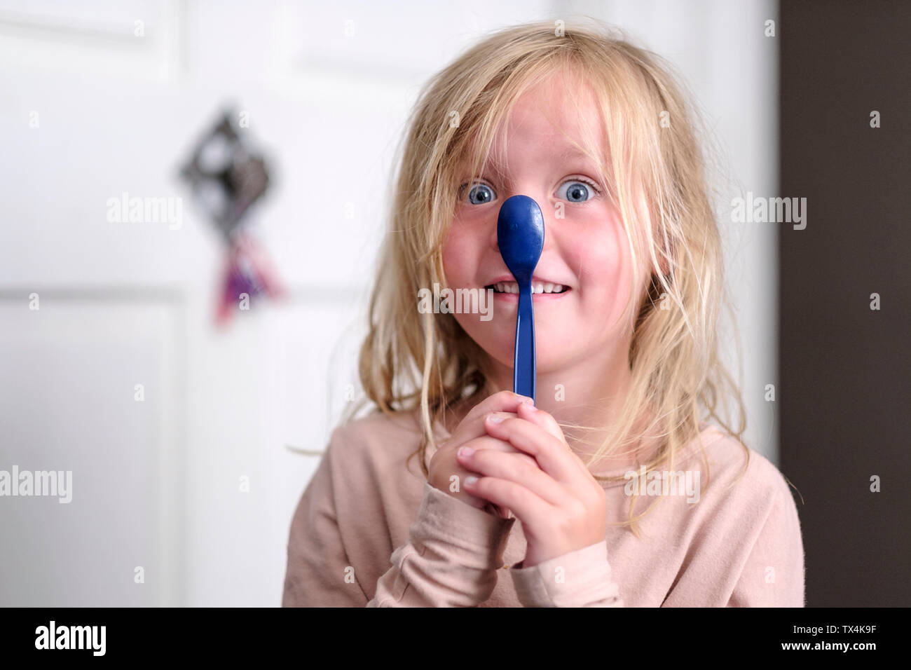 Portrait of smiling little girl playing with blue spoon Stock Photo - Alamy