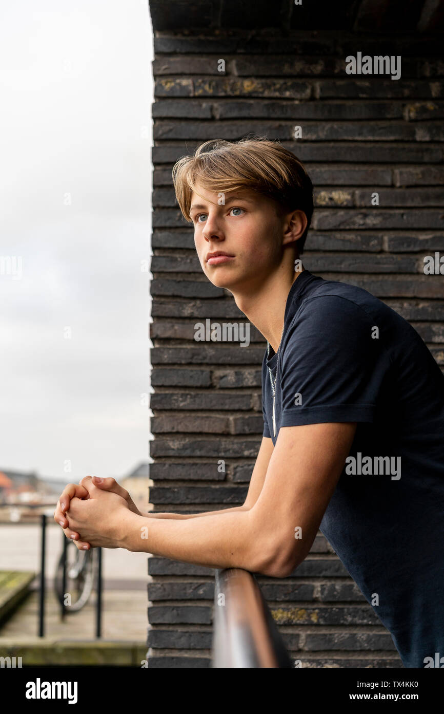 Portrait of young man leaning on railing Stock Photo - Alamy