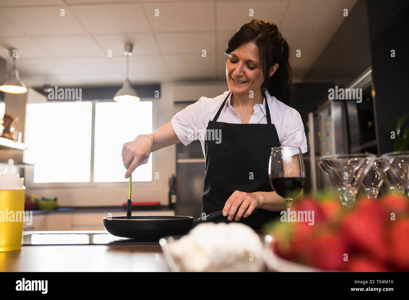 Woman cooking in kitchen using a pan Stock Photo - Alamy