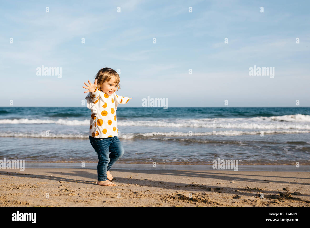 Happy little girl running barefoot on the beach Stock Photo - Alamy