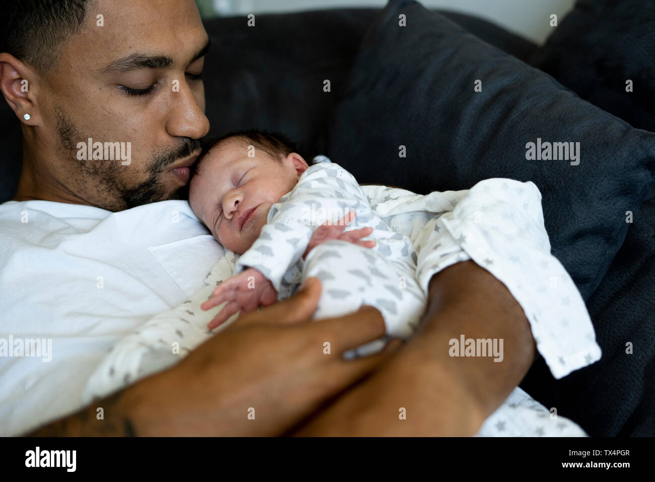 Father cuddling with newborn baby on couch Stock Photo - Alamy