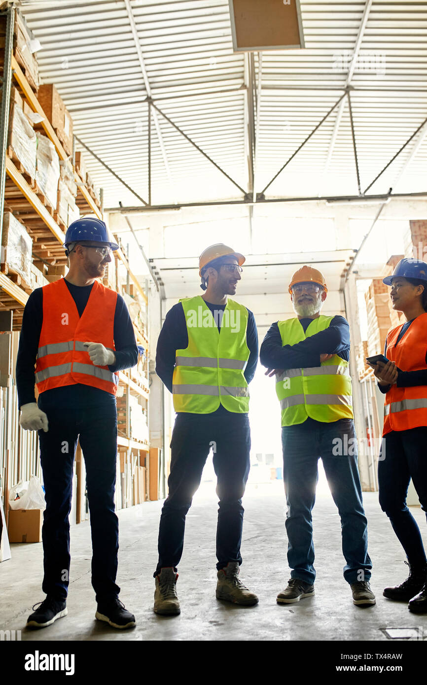Smiling workers standing in factory workshop talking Stock Photo - Alamy
