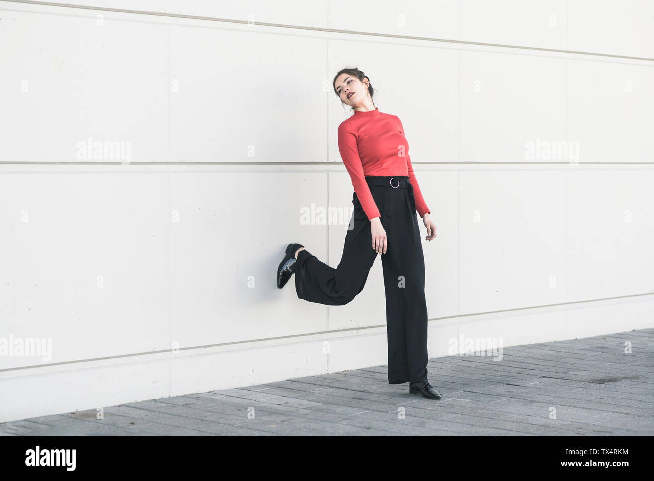 Elegant young woman leaning against a wall Stock Photo - Alamy