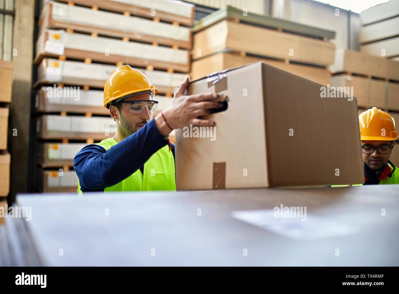 Worker carrying box in factory warehouse Stock Photo - Alamy