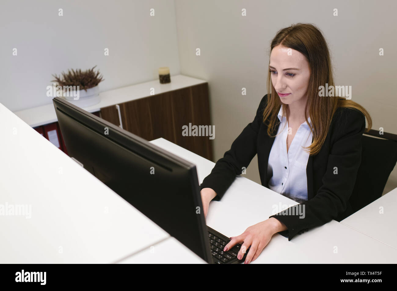 Young woman working at the reception desk in office Stock Photo - Alamy