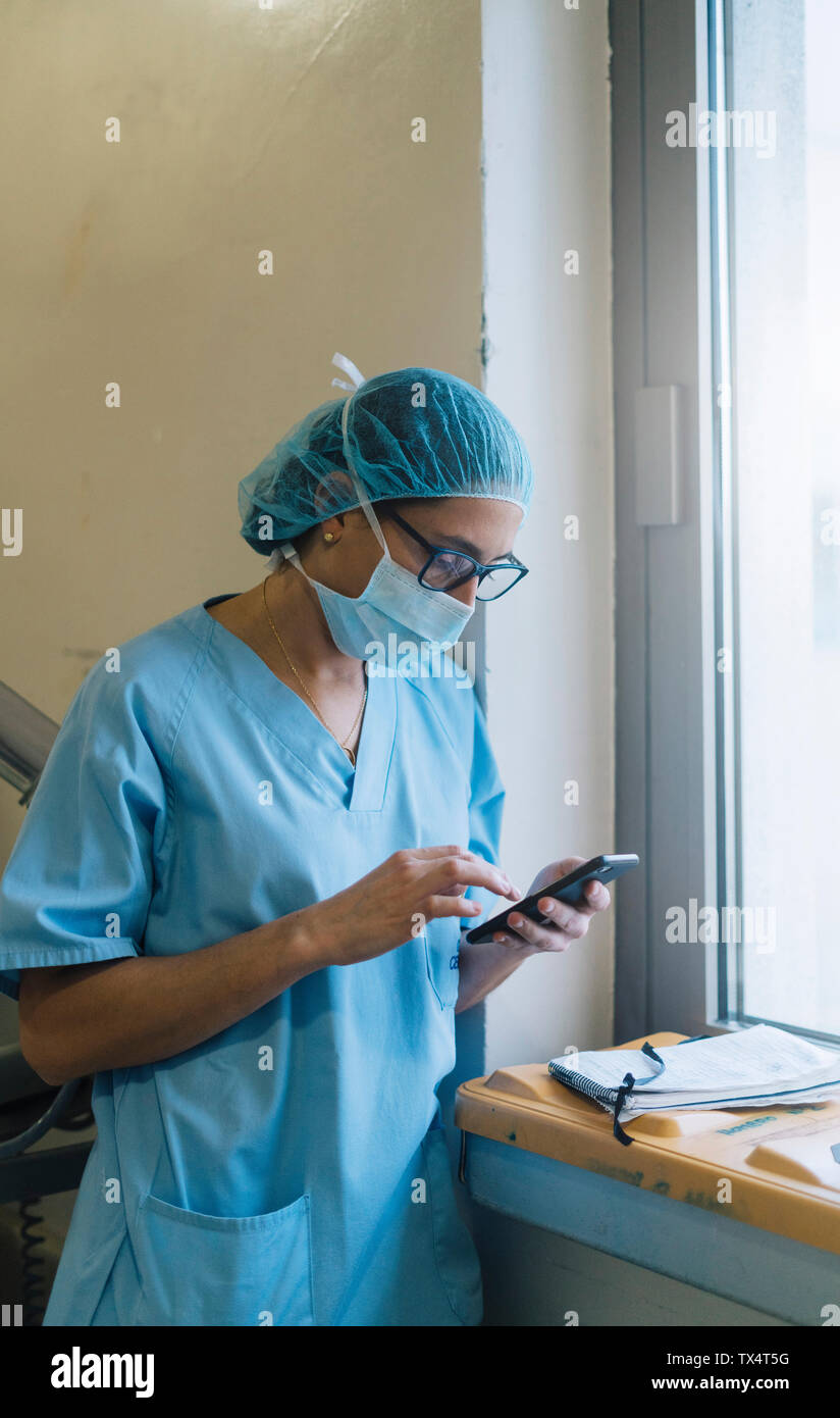 Female doctor using smartphone in hospital, preparing for surgery Stock ...