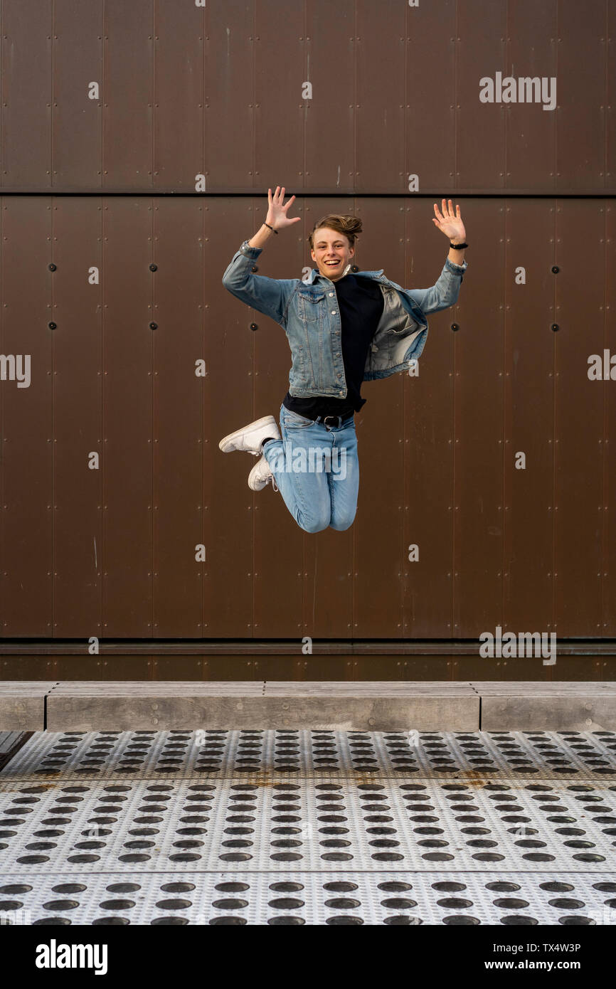 Young man jumping in front of a wall Stock Photo - Alamy