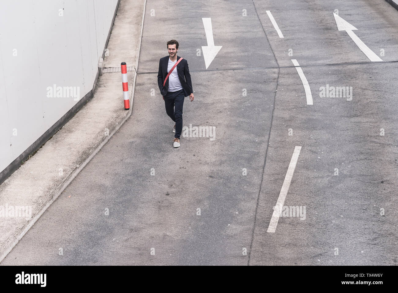 Confident businessman walking on road with arrow signs Stock Photo - Alamy