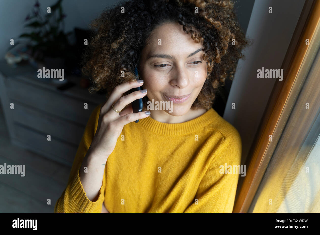 Woman talking on the phone, looking out of window Stock Photo - Alamy