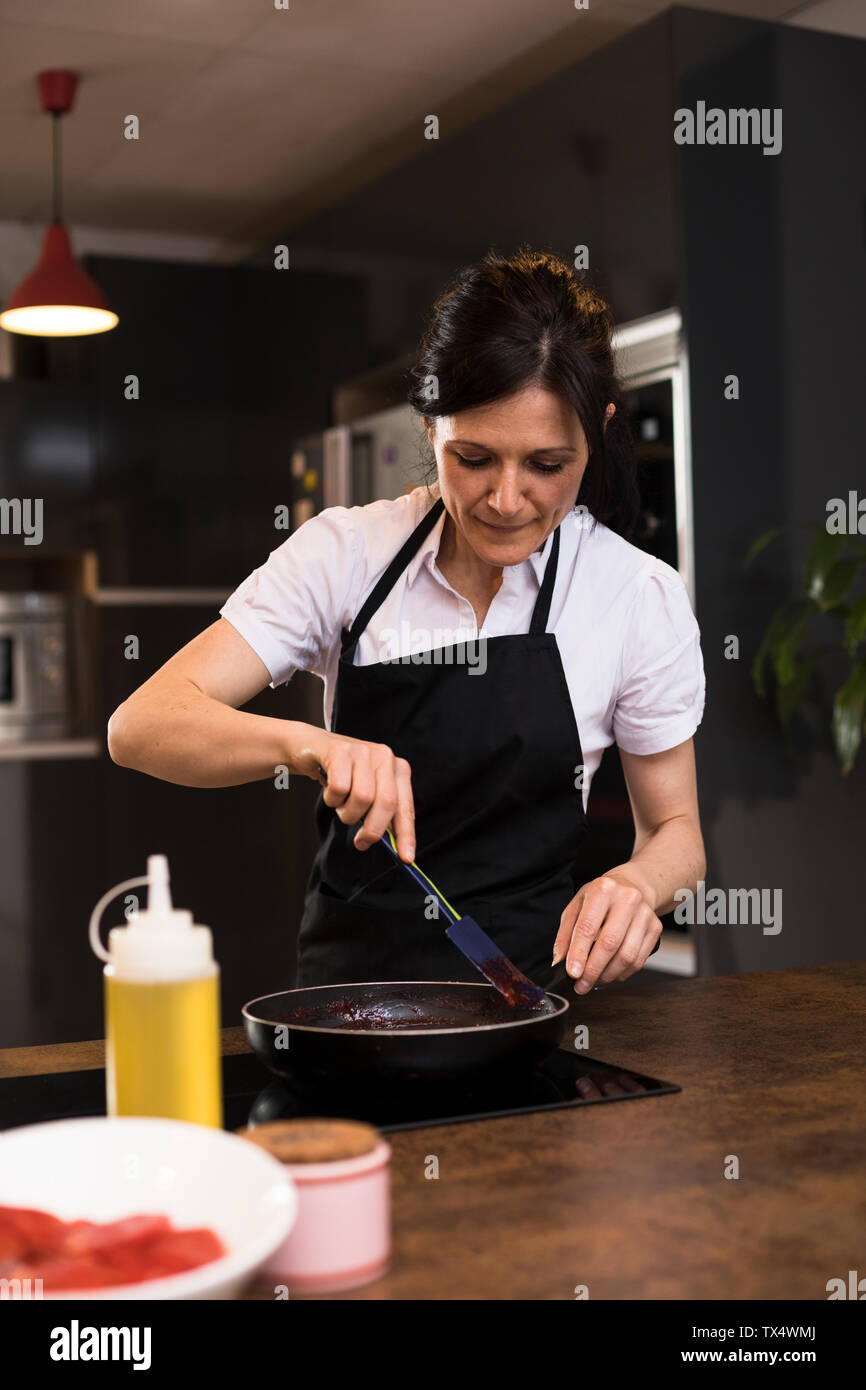 Woman cooking in kitchen using a pan Stock Photo - Alamy