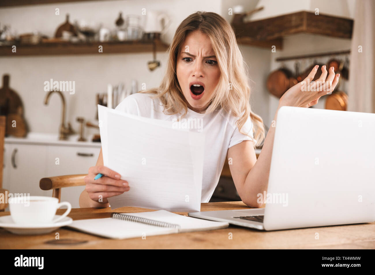 Image of stressed blond woman 20s wearing white t-shirt studying on ...