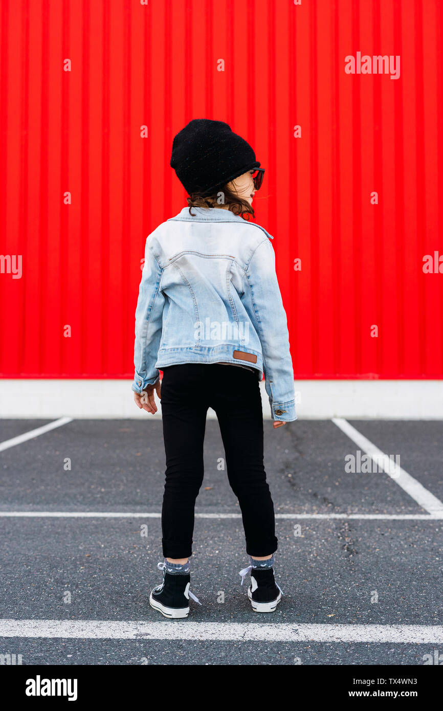 Back view of little girl wearing denim jacket, black cap and oversized ...