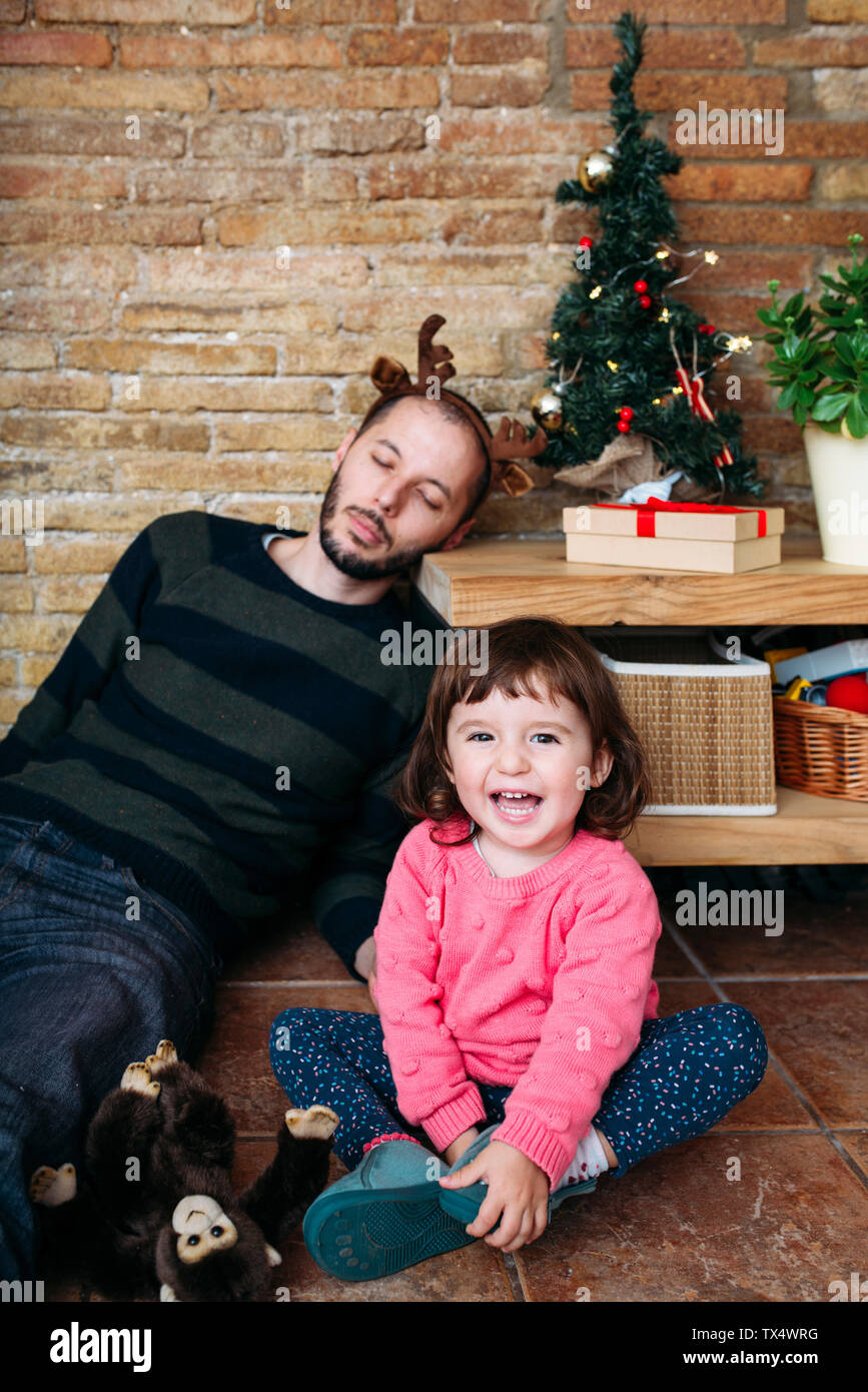 Exhausted father wearing reindeer antlers sleeping next to Christmas ...