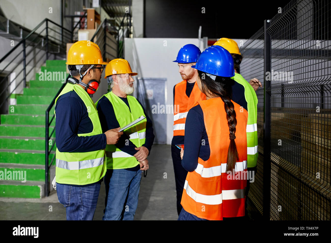 Workers standing in factory warehouse talking Stock Photo - Alamy