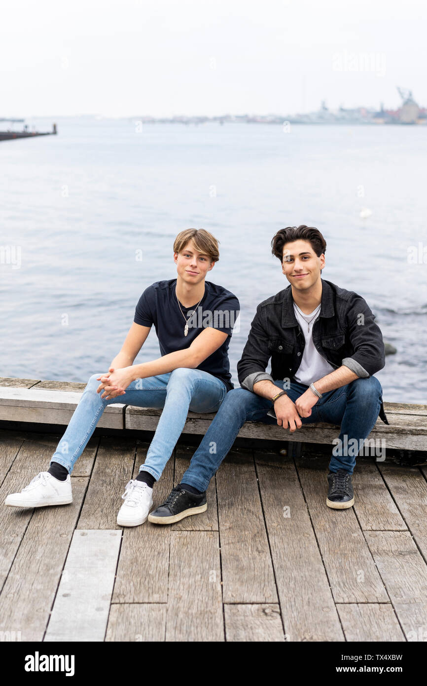Denmark, Copenhagen, portrait of two confident young men sitting at the ...