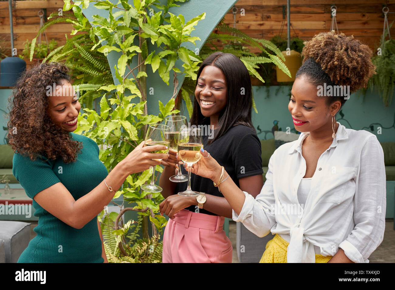 Three happy friends toasting with white wine Stock Photo - Alamy